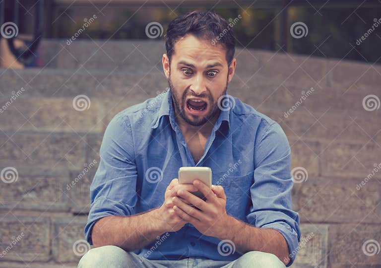 Shocked Man Looking At Mobile Phone Seeing Bad News Or Reading Text