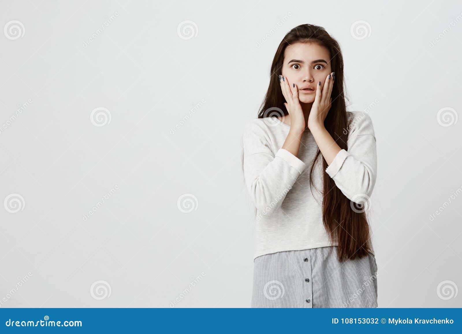 Shocked Stunned Emotional Brunette Girl Keeps Hands On Cheeks Being