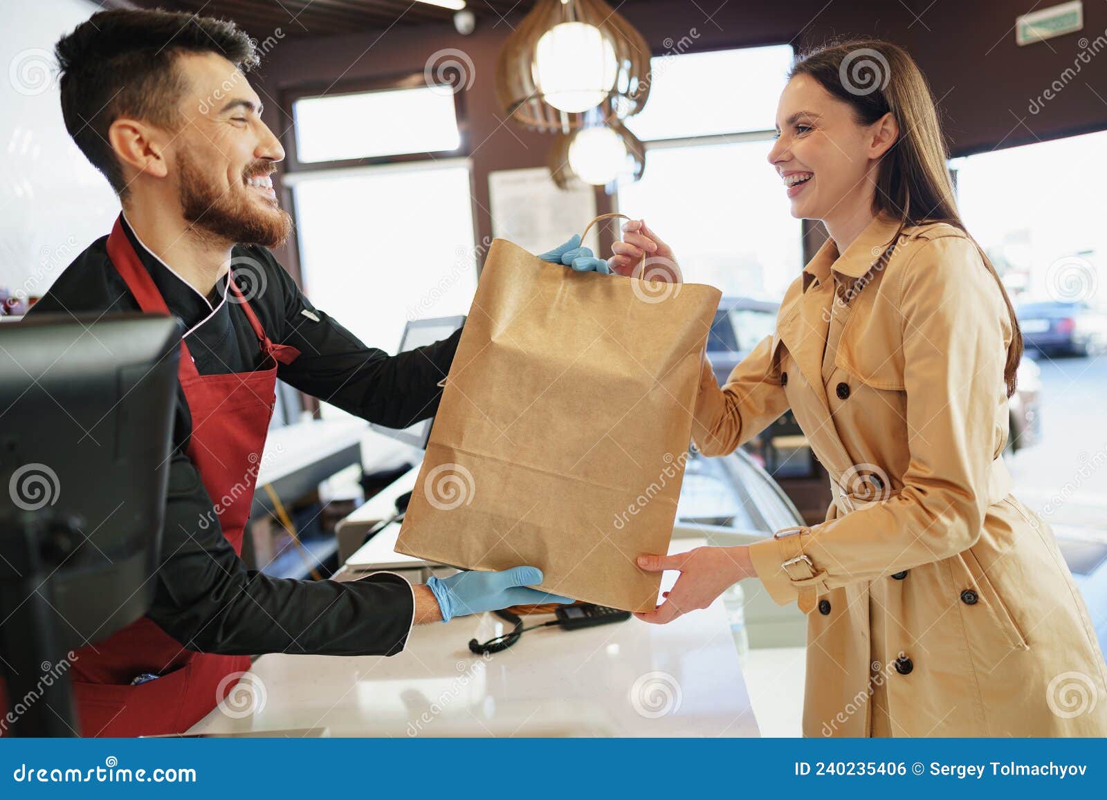 Shop Assistant Handling Shopping Bag To Female Customer In Grocery