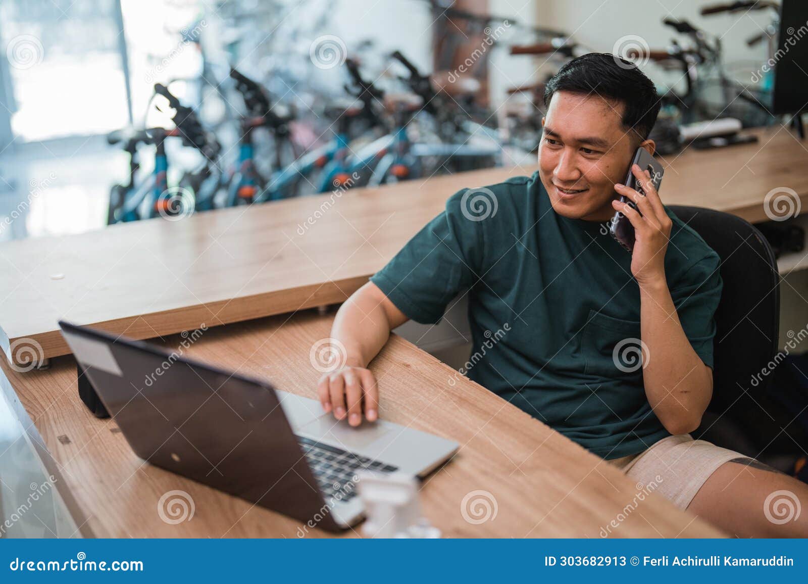 Shopkeeper Man Makes a Call while Working on a Laptop Computer Stock ...