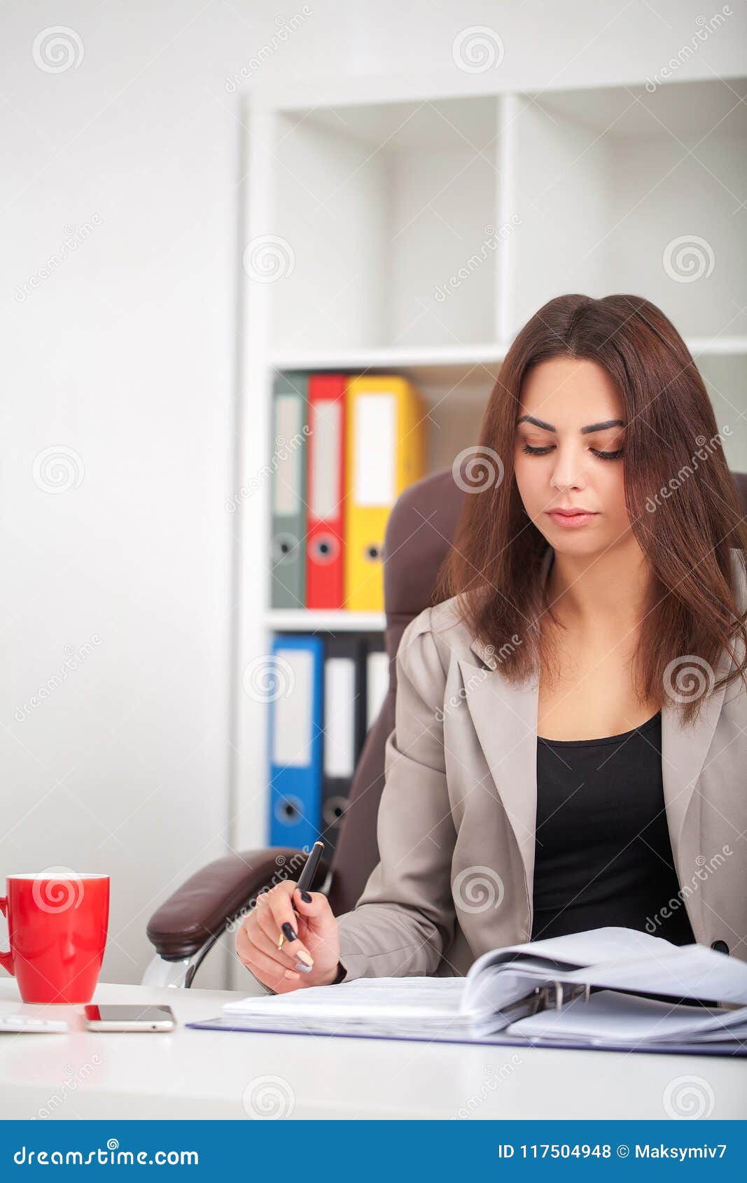 Shot Of Beautiful Young Woman Sitting At Her Work Desk Going Through