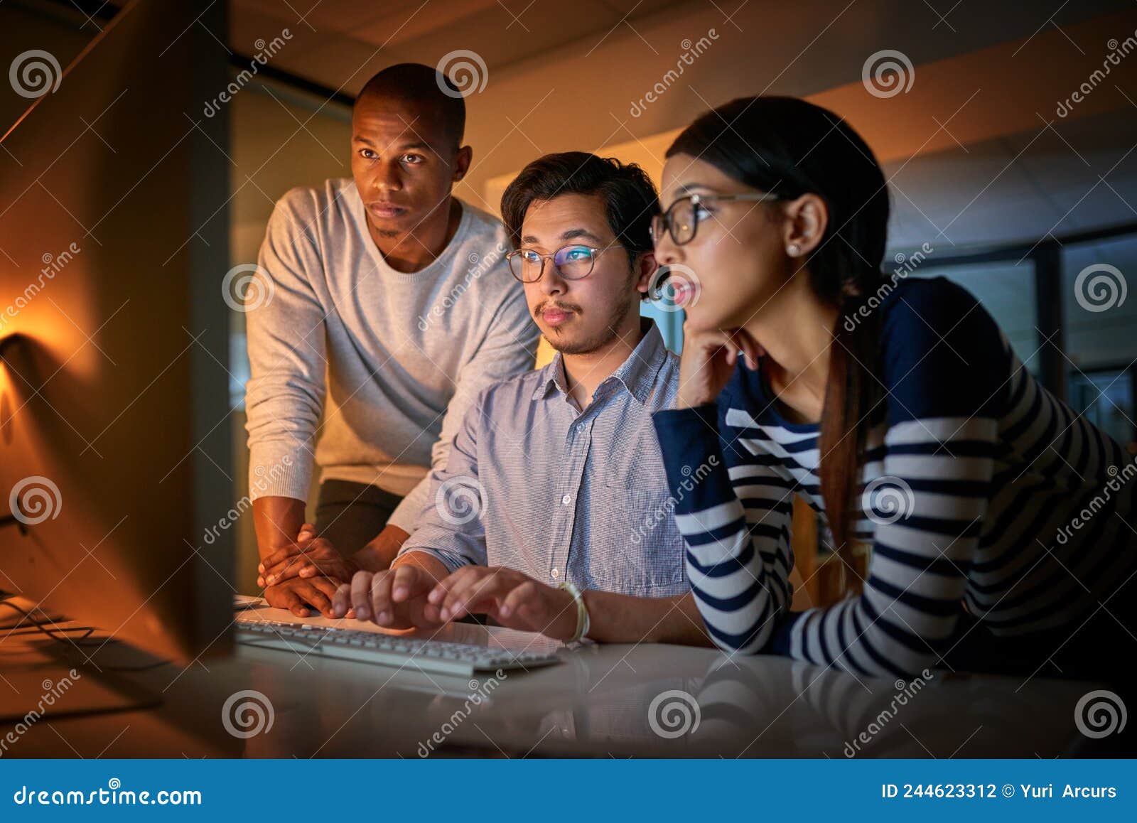 Getting Work Done Together. Shot of Computer Programmers Working Together Late in the Office ...