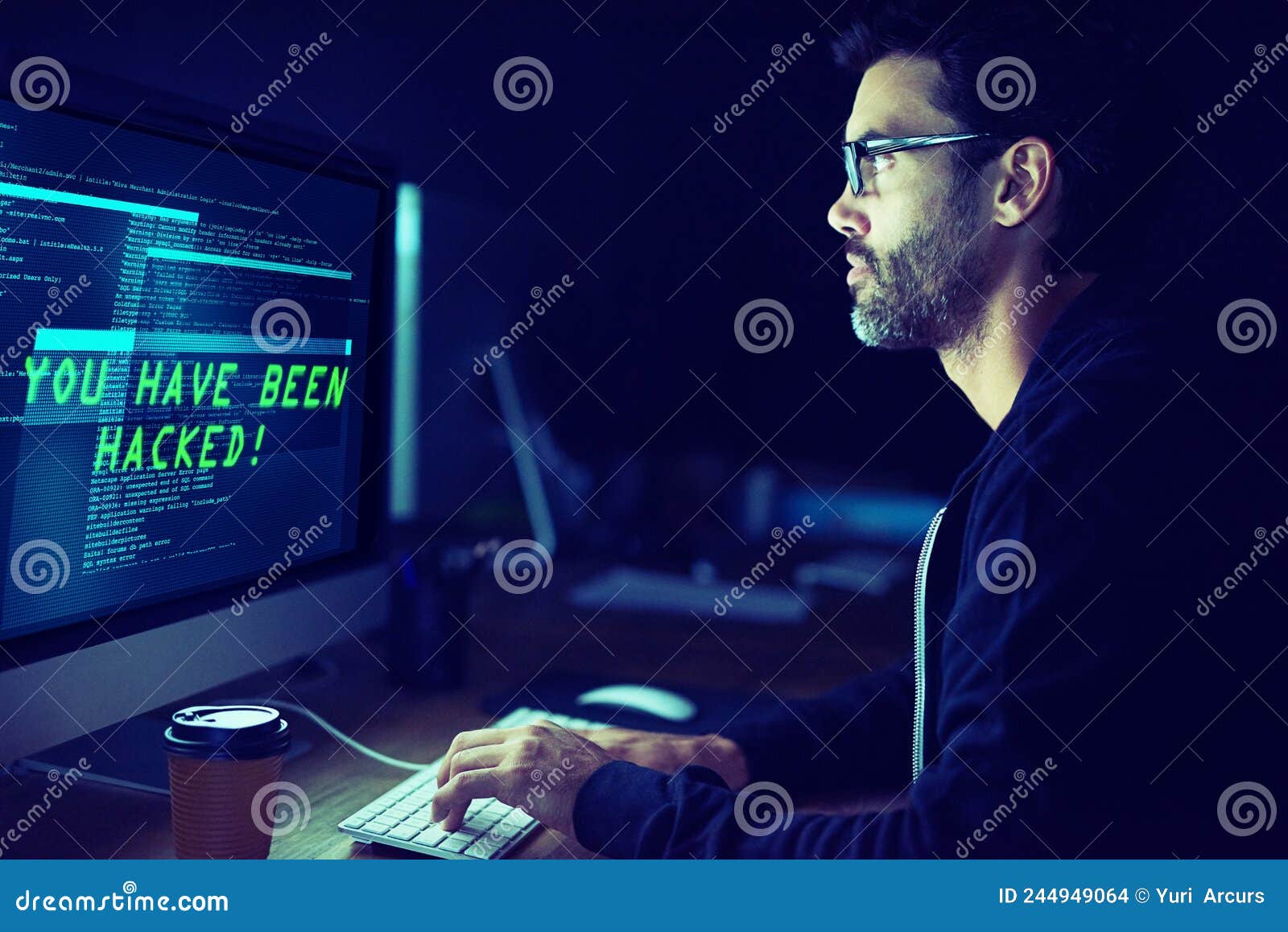 He Could Be Coming for You. Shot of a Focussed Computer Hacker Using a Computer in the Dark ...