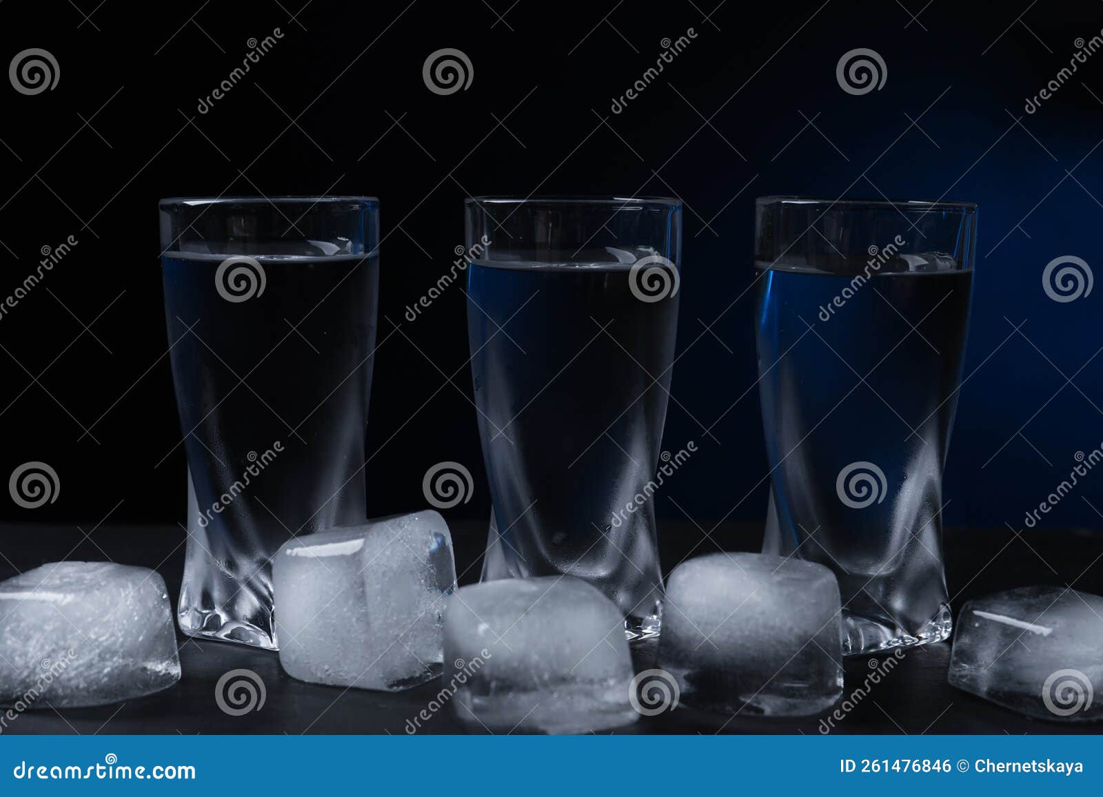 Shot Glasses of Vodka with Ice Cubes on Black Table Against Dark ...