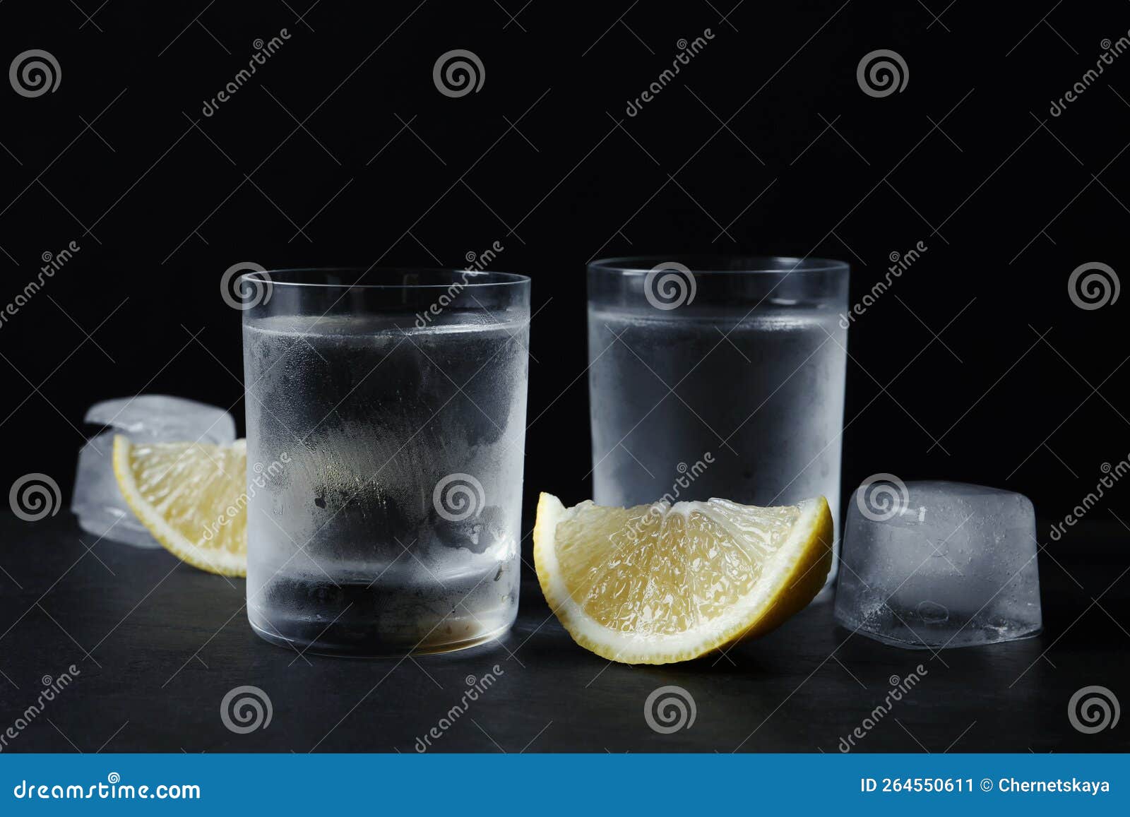 Shot Glasses of Vodka with Lemon Slices and Ice on Black Background ...
