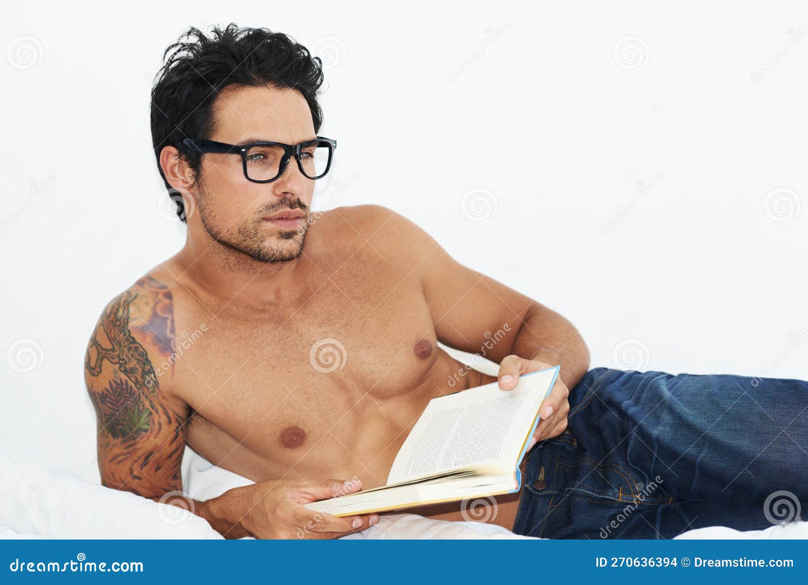 Enjoying a Deep Read.... Shot of a Handsome Young Man Lying on His Bed ...