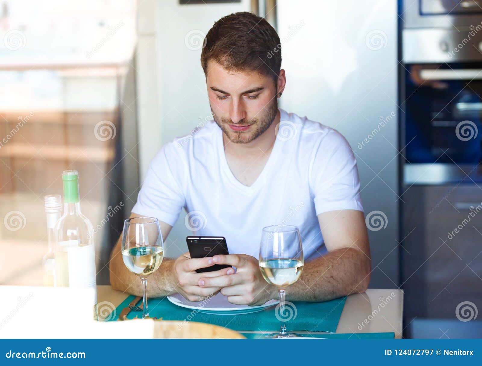 Handsome Young Man Using His Mobile Phone in the Kitchen at Home. Stock ...