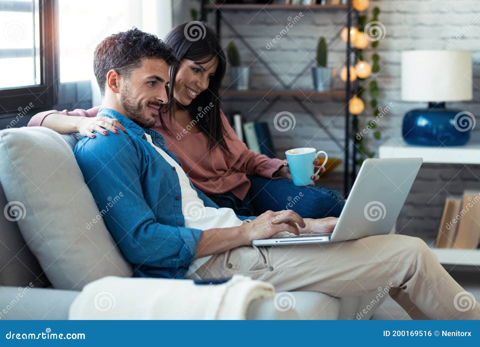 Happy Beautiful Couple Using Computer while Sitting on the Couch at ...