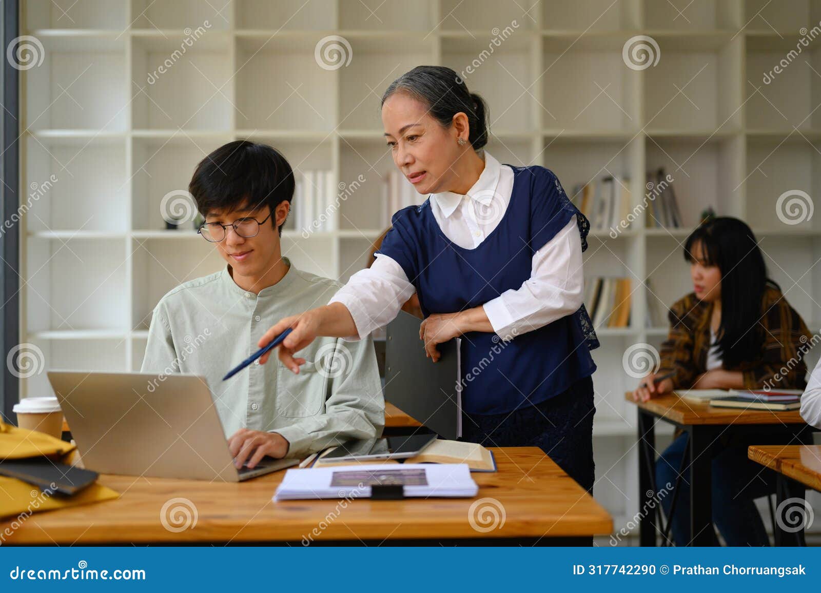 Shot of Mature Professor Walking and Checking Student Homework in the ...