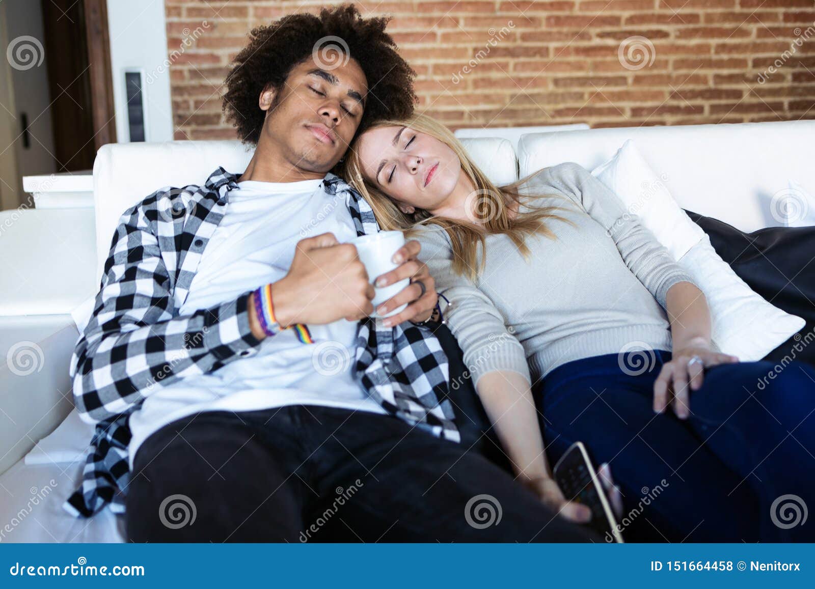 Relaxed Young Couple Who Has Fallen Asleep While Watching Tv On The