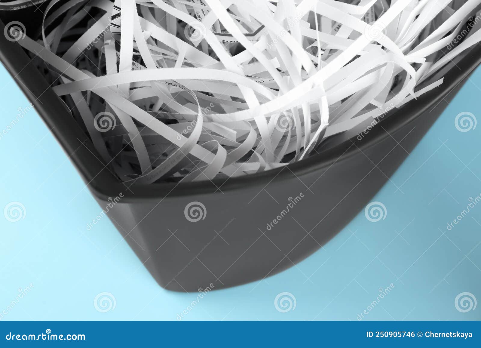 Shredded Paper Strips in Trash Bin on Light Blue Background, Closeup ...