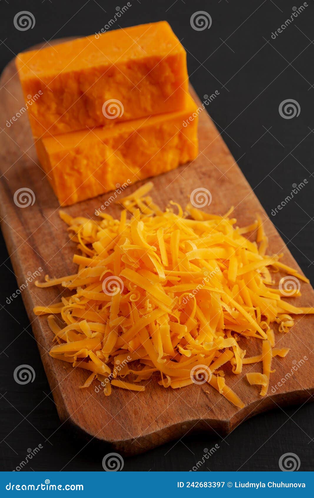Shredded Sharp Cheddar Cheese on a Rustic Wooden Board on a Black ...