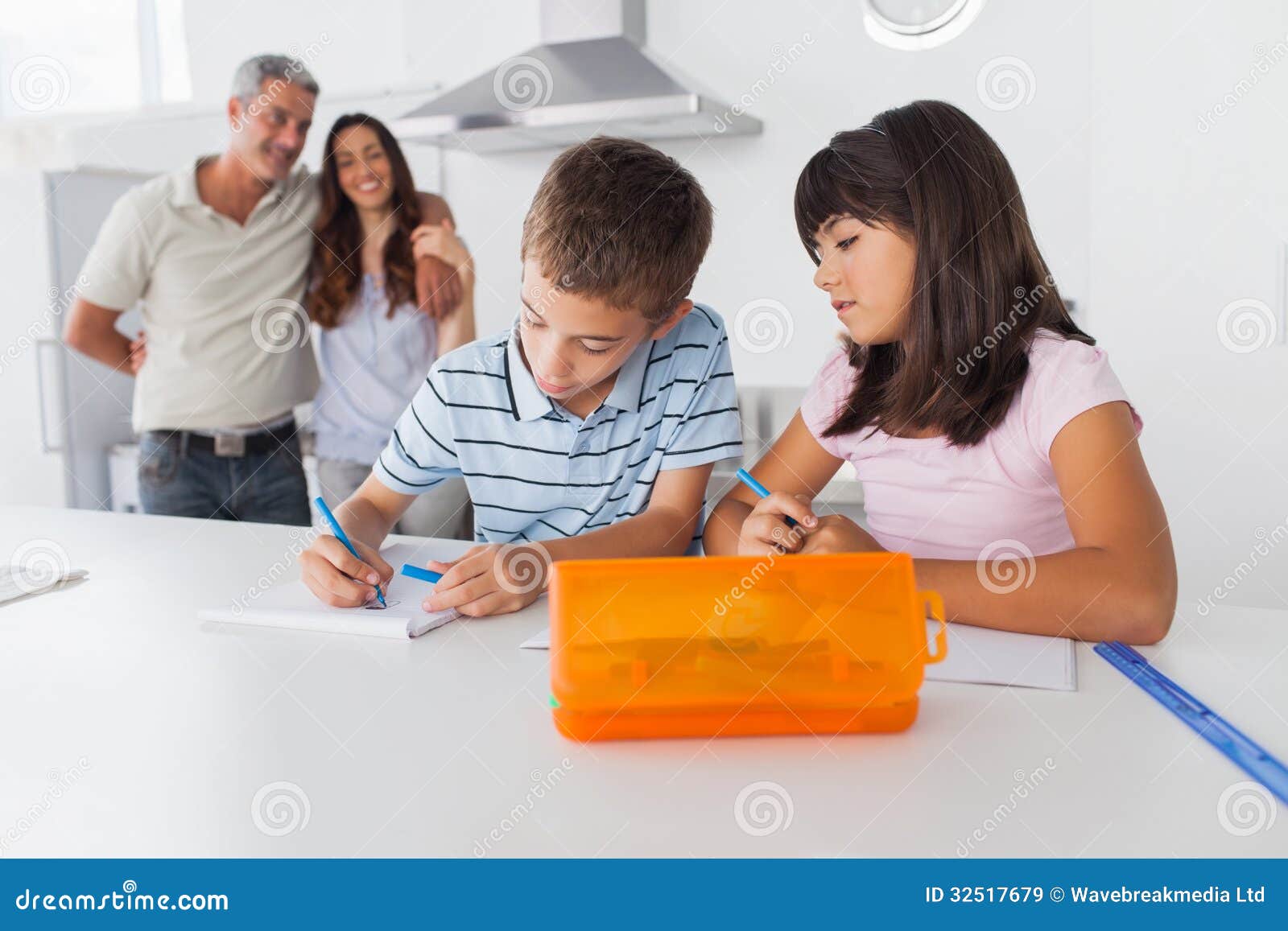 Siblings Drawing Together In Kitchen With Their Parents Smiling Stock ...