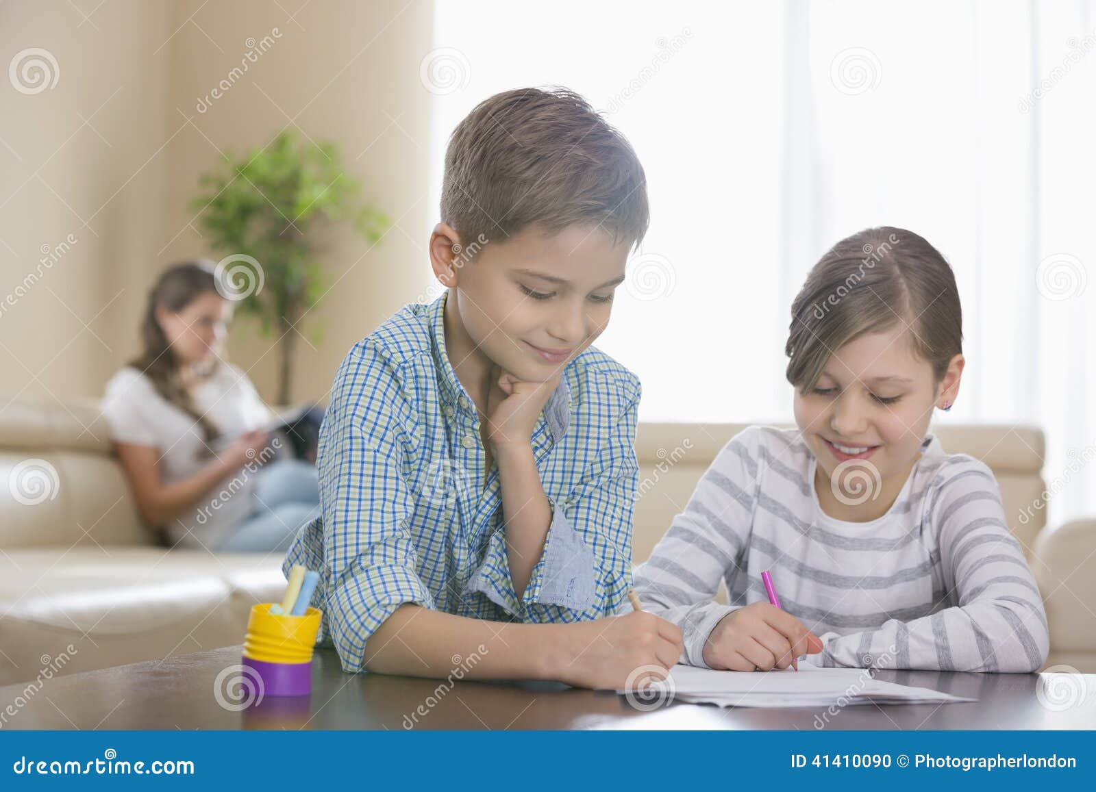 Siblings Drawing Together In Kitchen With Their Parents Smiling Stock ...