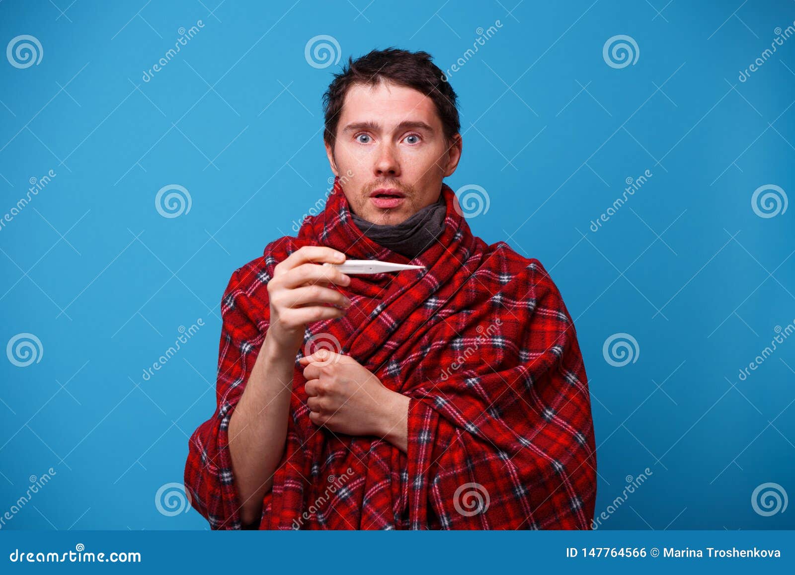 A Sick Man Wrapped in a Blanket is Standing with a Thermometer in His ...
