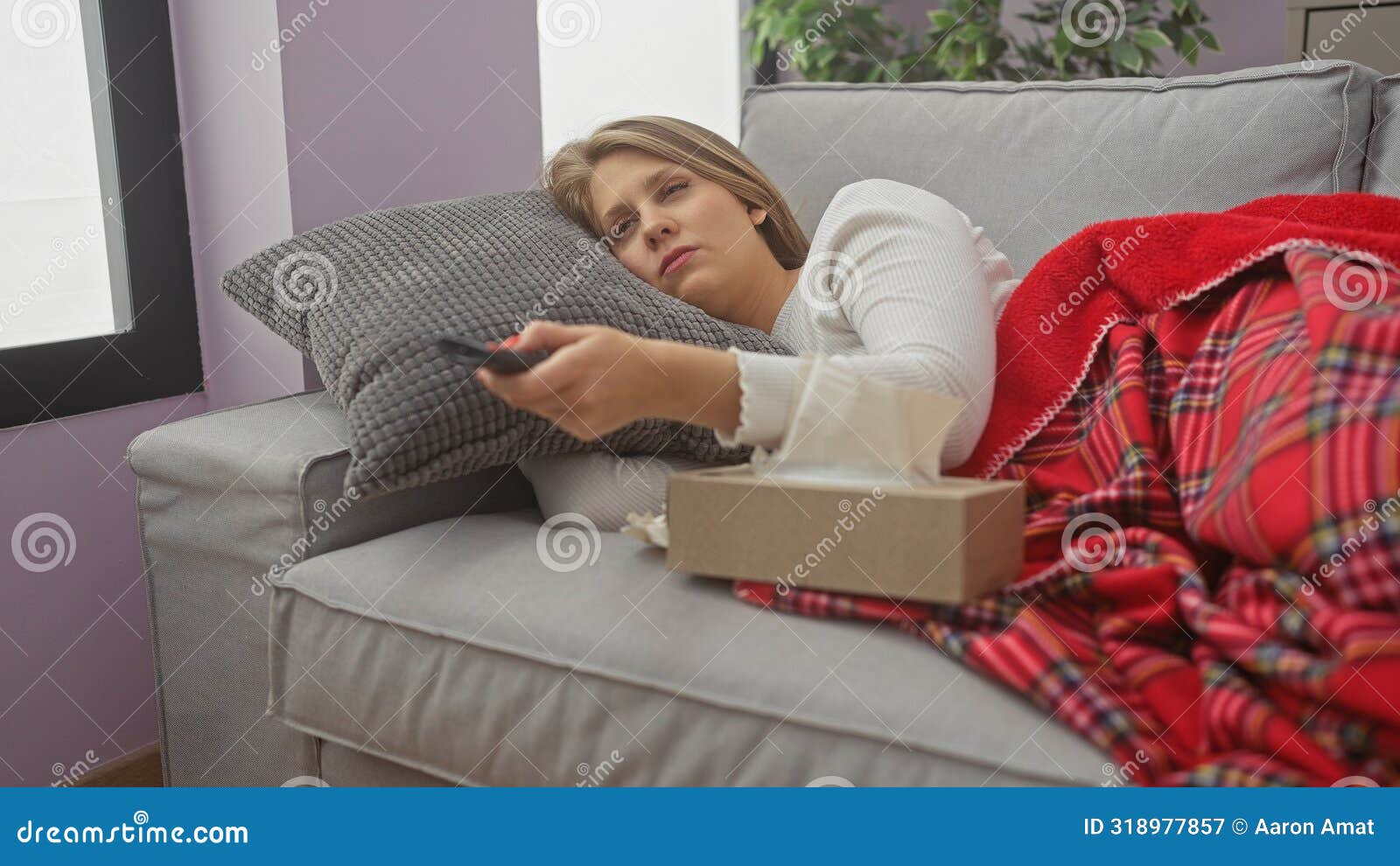 Sick Woman Reclining on Couch with Tissues and Remote, Covered in ...
