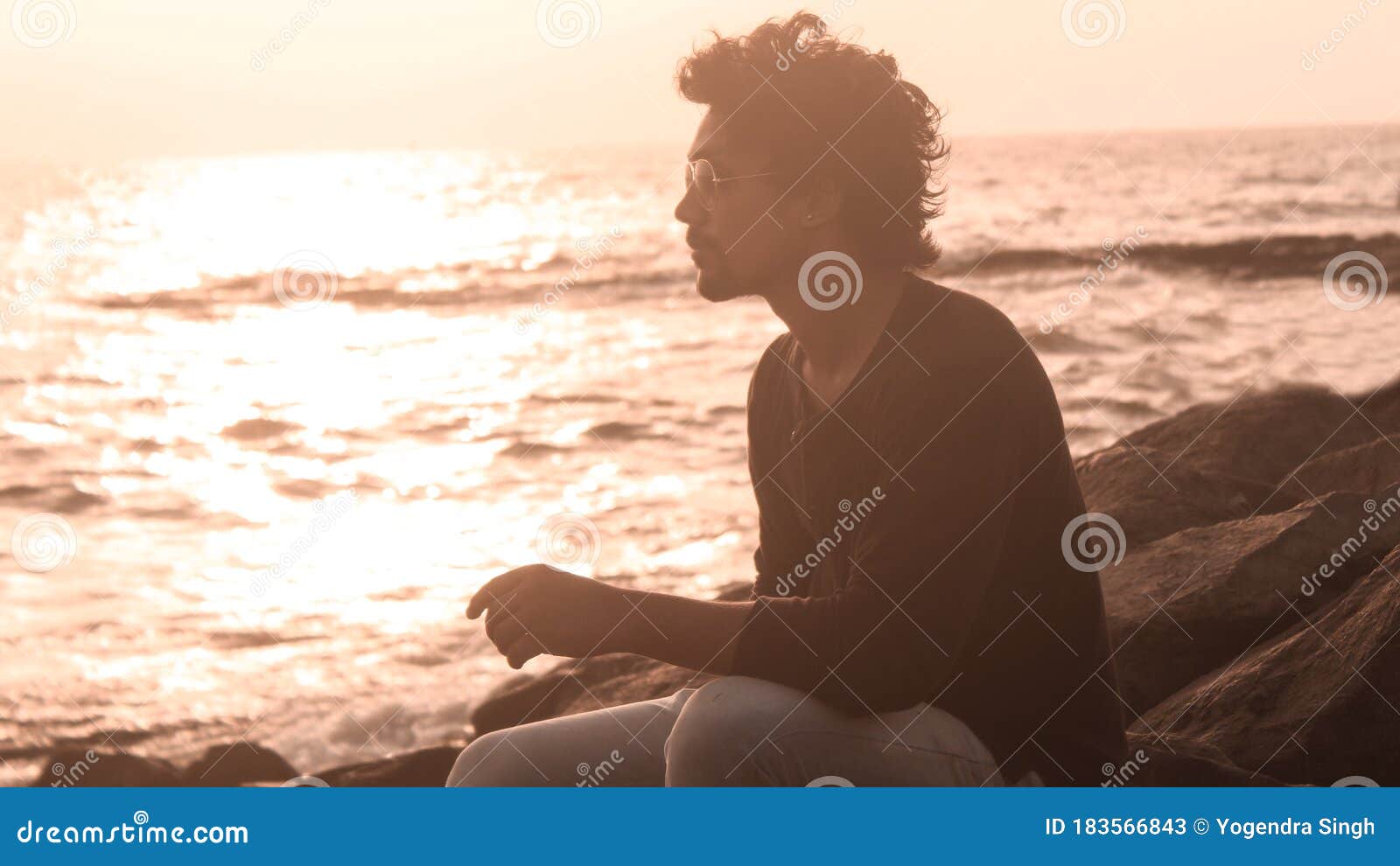 Side Profile of the Boy Sitting on the Rocks during Sunset, with Long ...