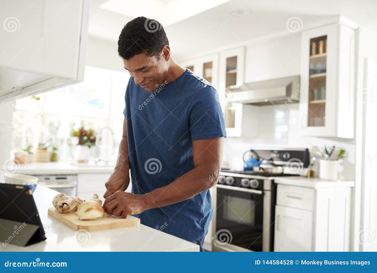 Side View of Adult Man Standing at Kitchen Worktop Preparing Food Using ...