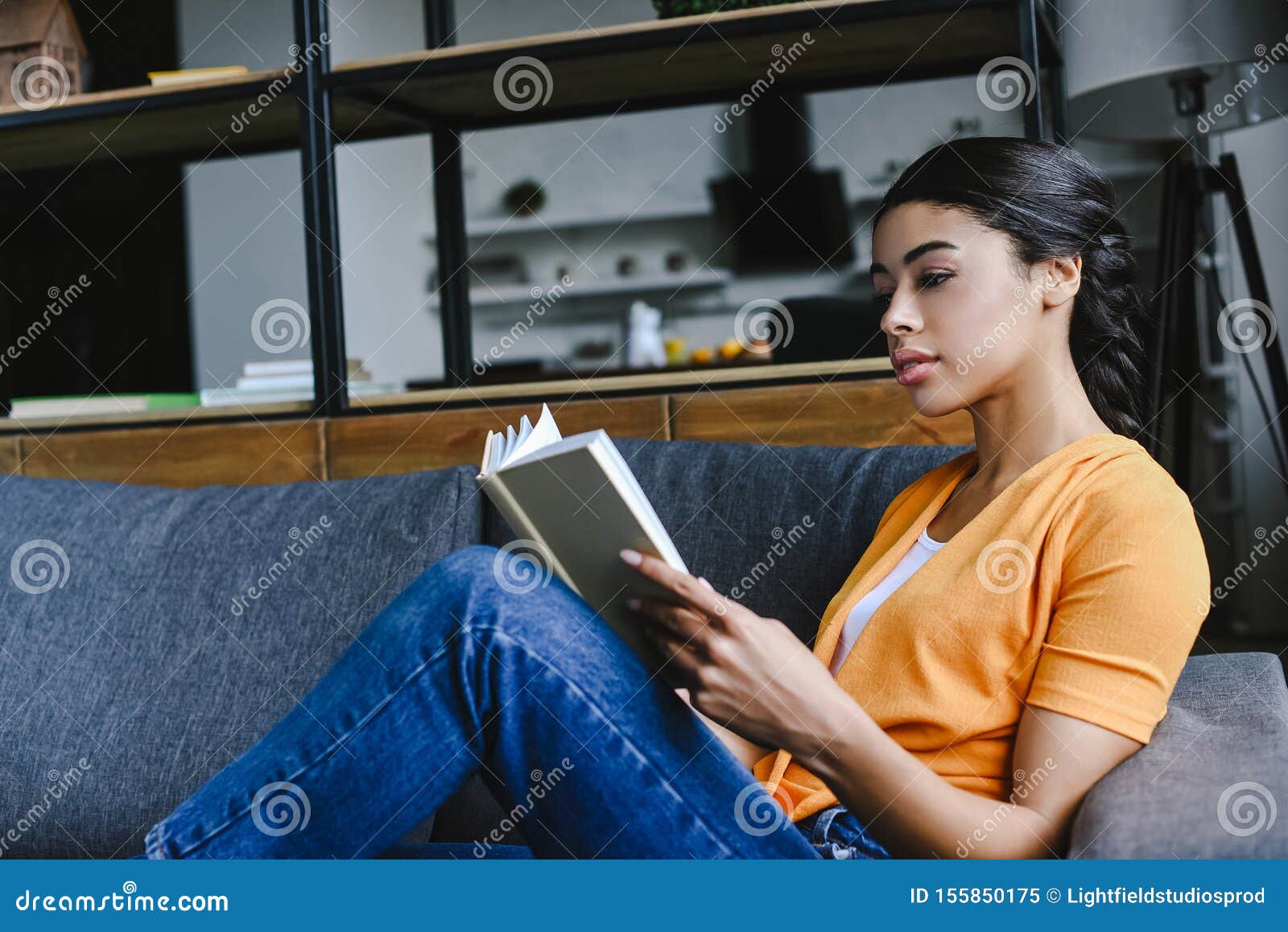 Side View Of Beautiful Mixed Race Girl In Orange Shirt Reading Book In
