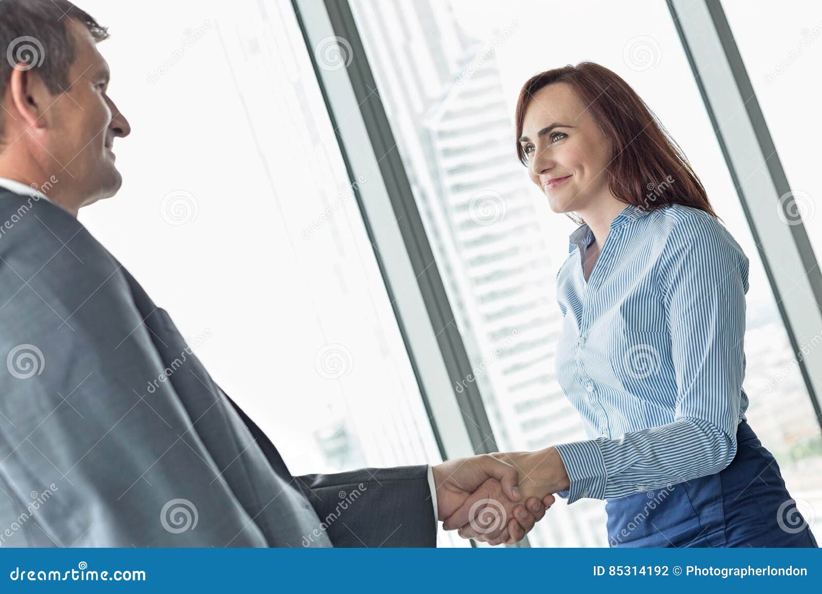 Side View of Business People Shaking Hands in Office Stock Photo ...