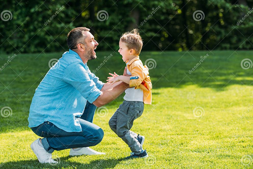 Side View Of Cheerful Father And Son Hugging And Smiling Each Other
