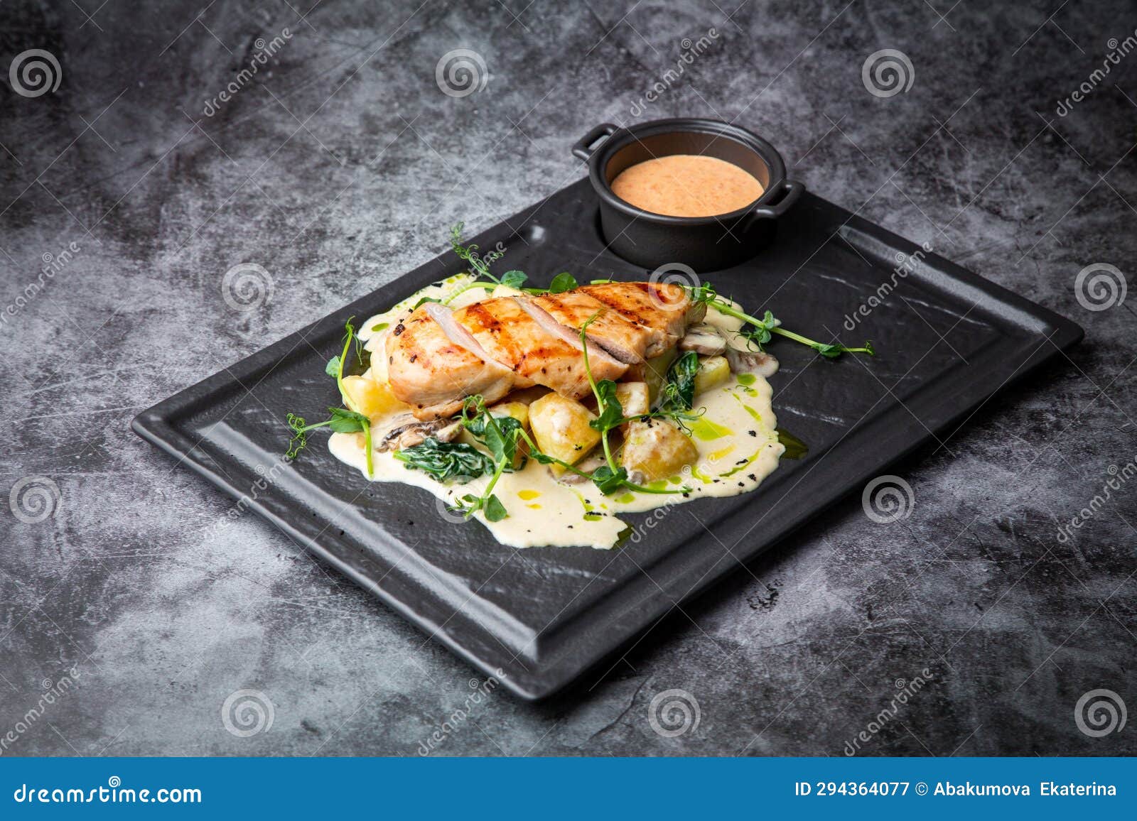 Side View of Chicken Breast in Cheese Sauce with Herbs on a Black Tray ...