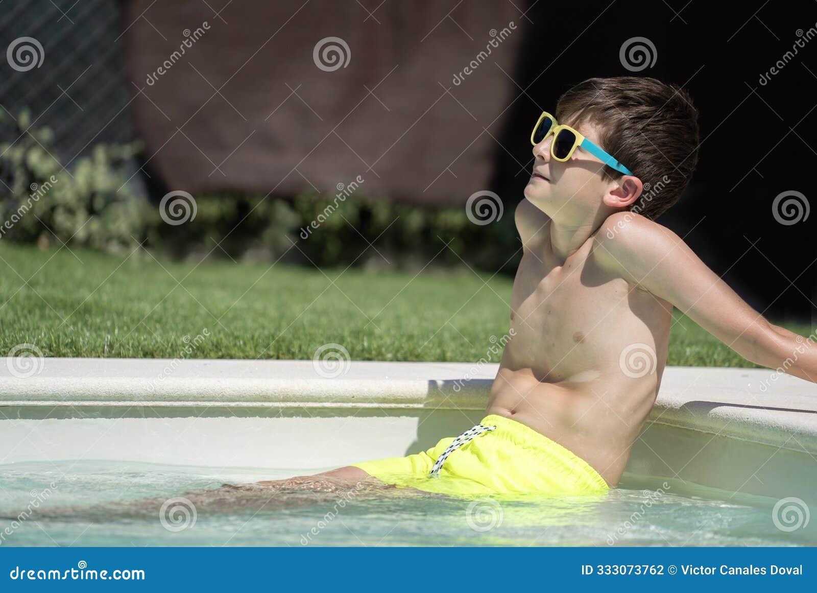 Side View of a Child Boy Relaxed Sitting in a Pool and Sunbathing with ...