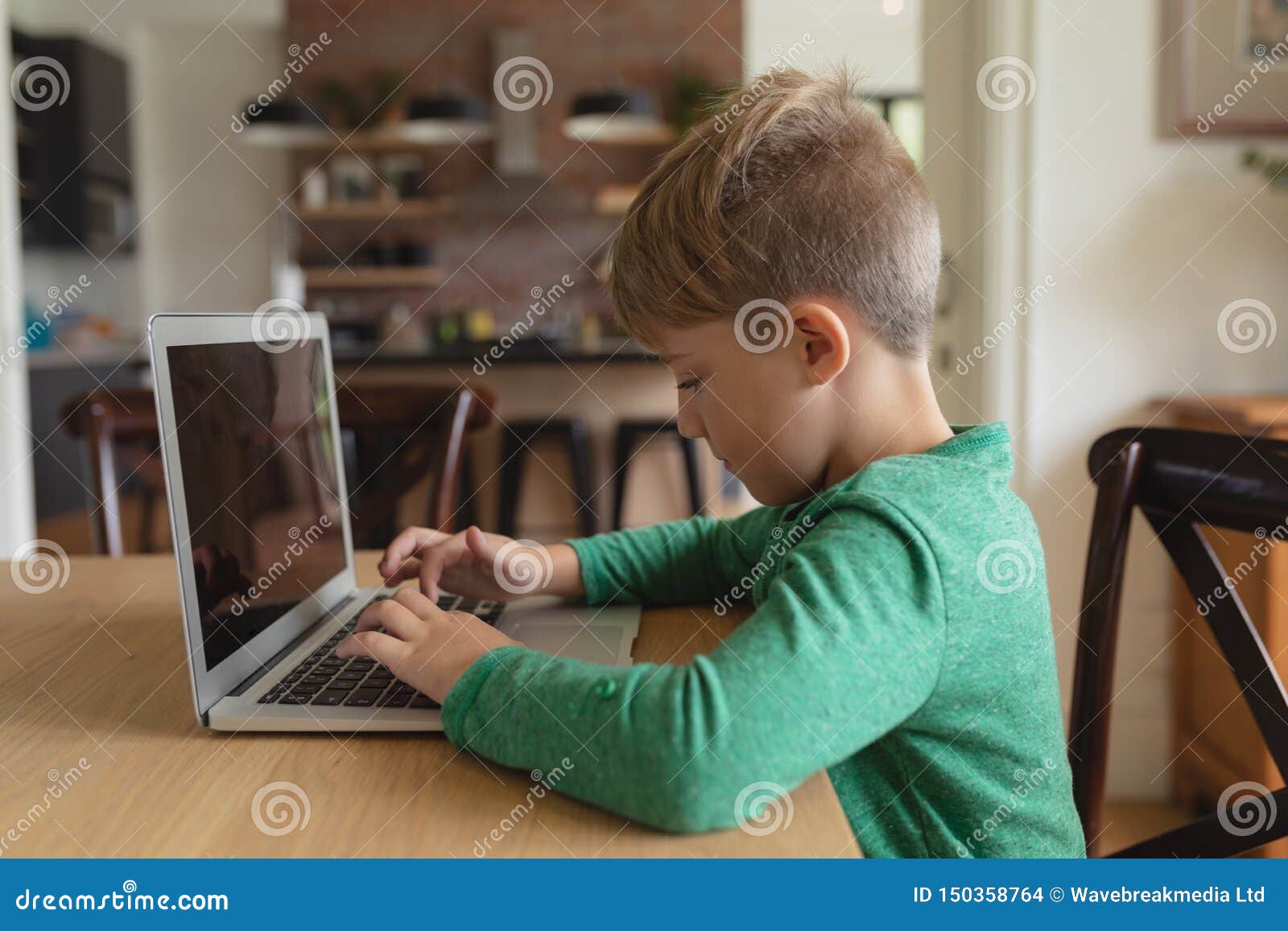 Cute Boy Using Laptop at Dining Table in a Comfortable Home Stock Photo ...