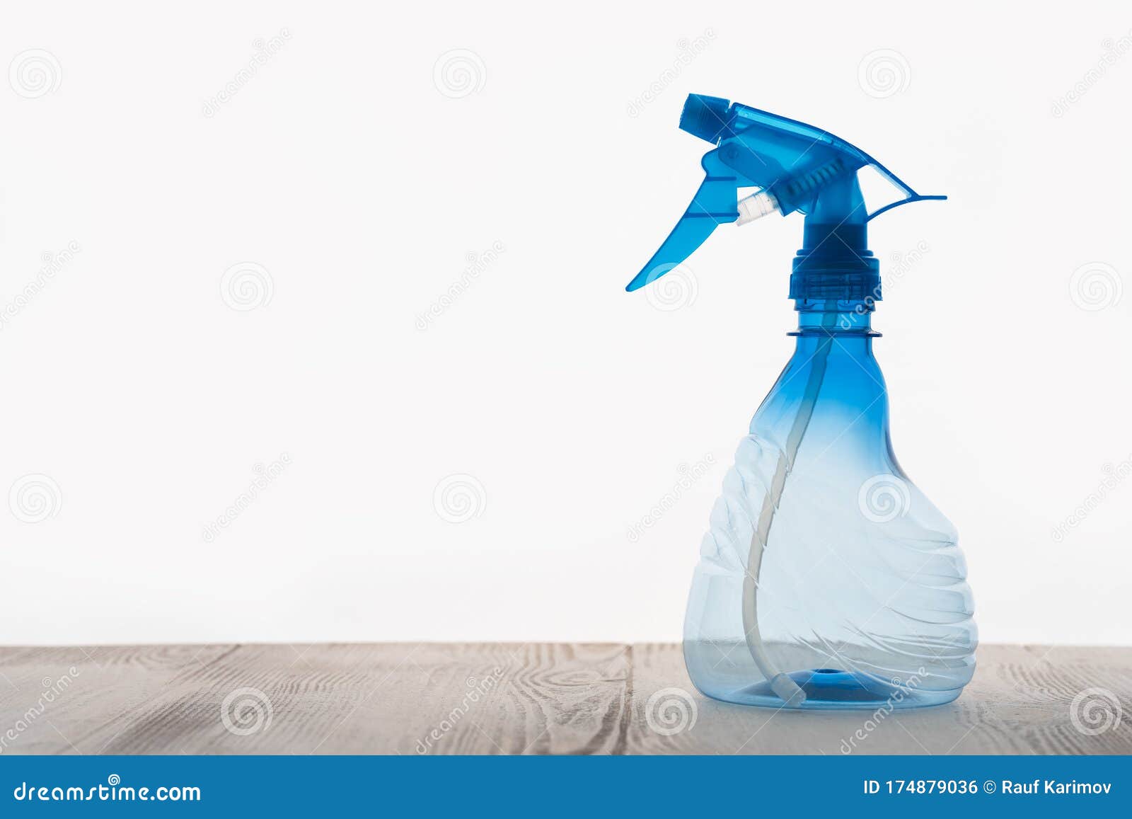 A Manual Plastic Spray Bottle Stands on a Wooden Table with a White ...