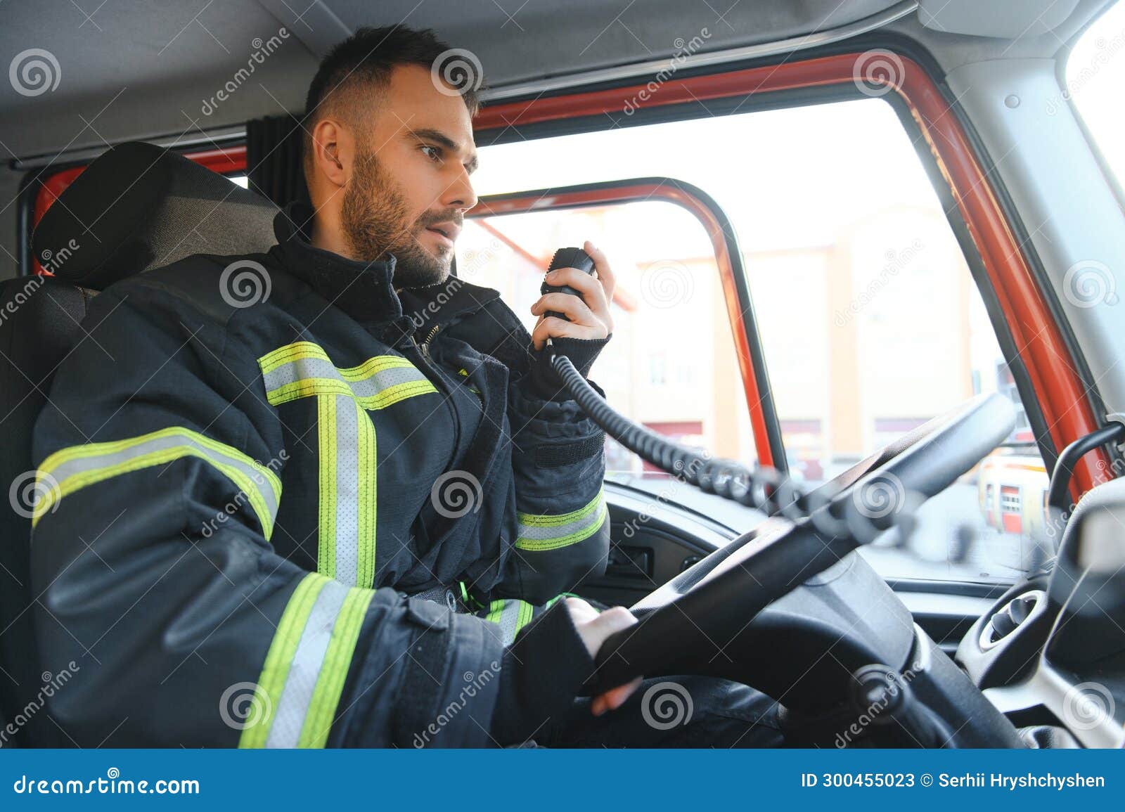 Side View of Firefighter in Protective Uniform Driving Fire Engine ...