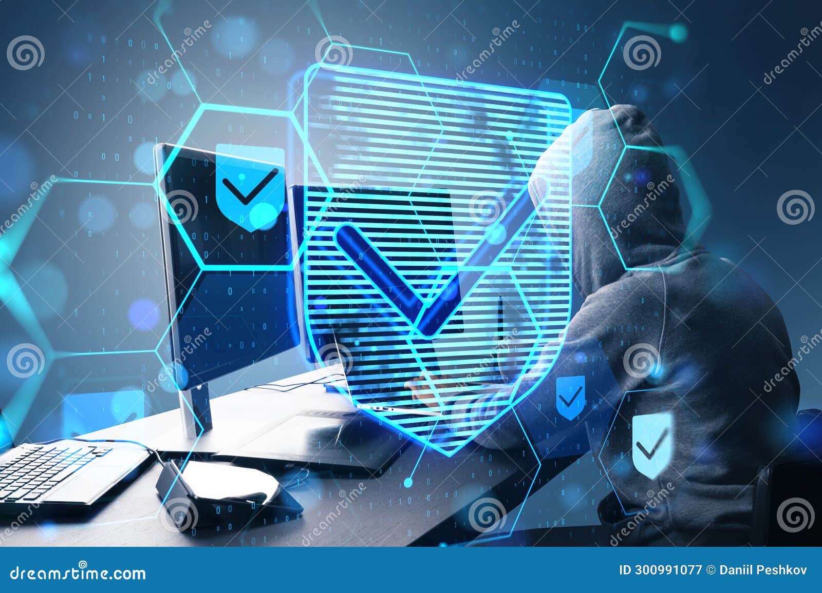 Side View Of Hacker At Desktop Using Laptop With Glowing Hexagonal Shield Hologram With Binary