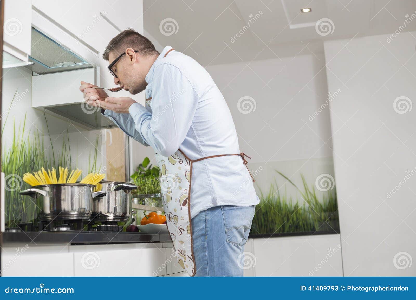 Side View of Man Tasting Food while Cooking in Kitchen Stock Image ...