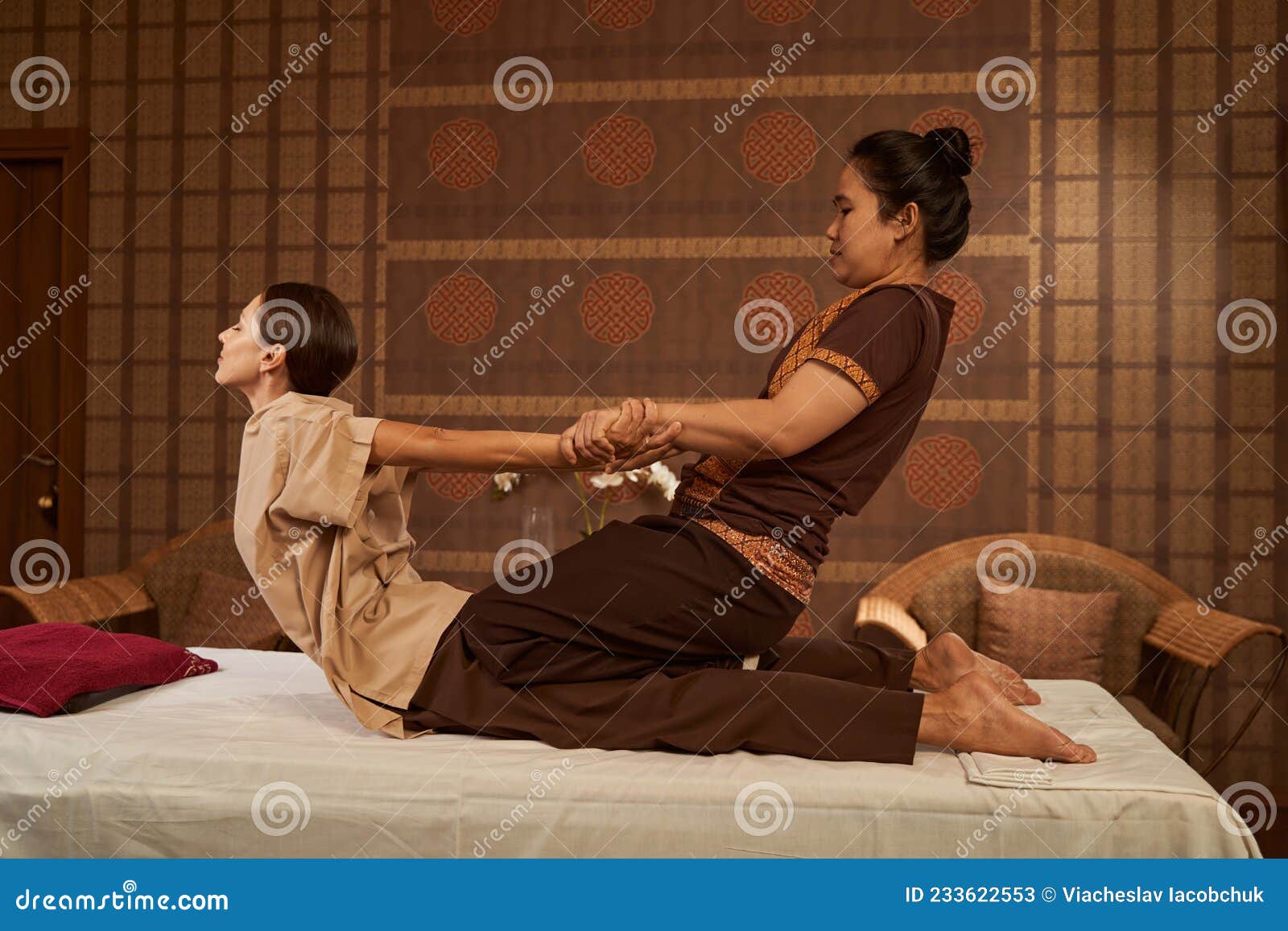 Practitioner Stretching Her Client Back Muscles during Thai Massage ...