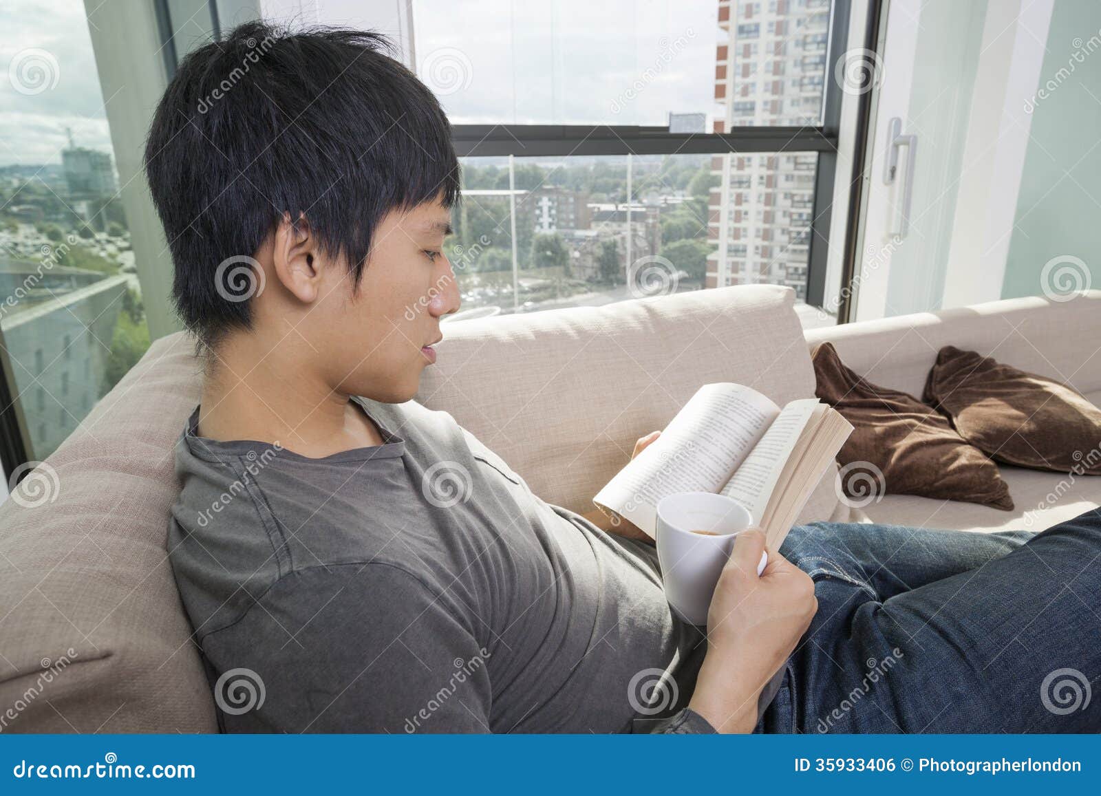 Side View of Mid Adult Man Having Coffee while Reading Book on Sofa ...