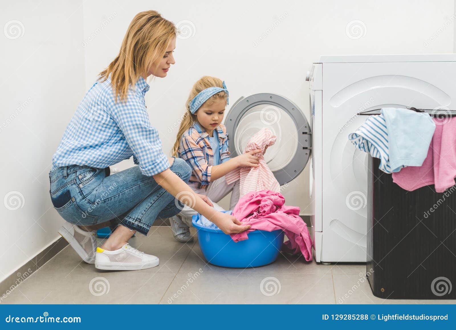 Side View of Mother and Daughter Putting Laundry into Washing Machine ...