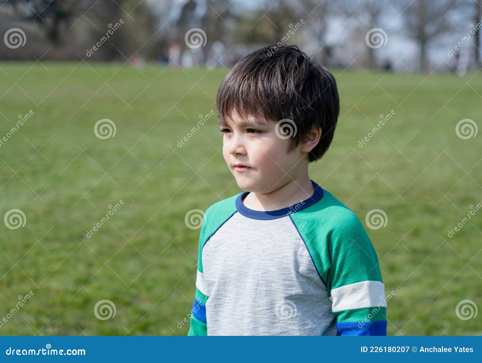Side View Portrait of Young Boy Standing in the Park with Blurry Grass ...