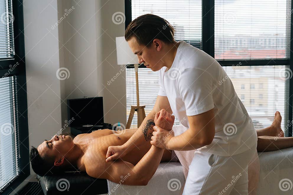 Side View Of Professional Male Masseur With Strong Hands Massaging