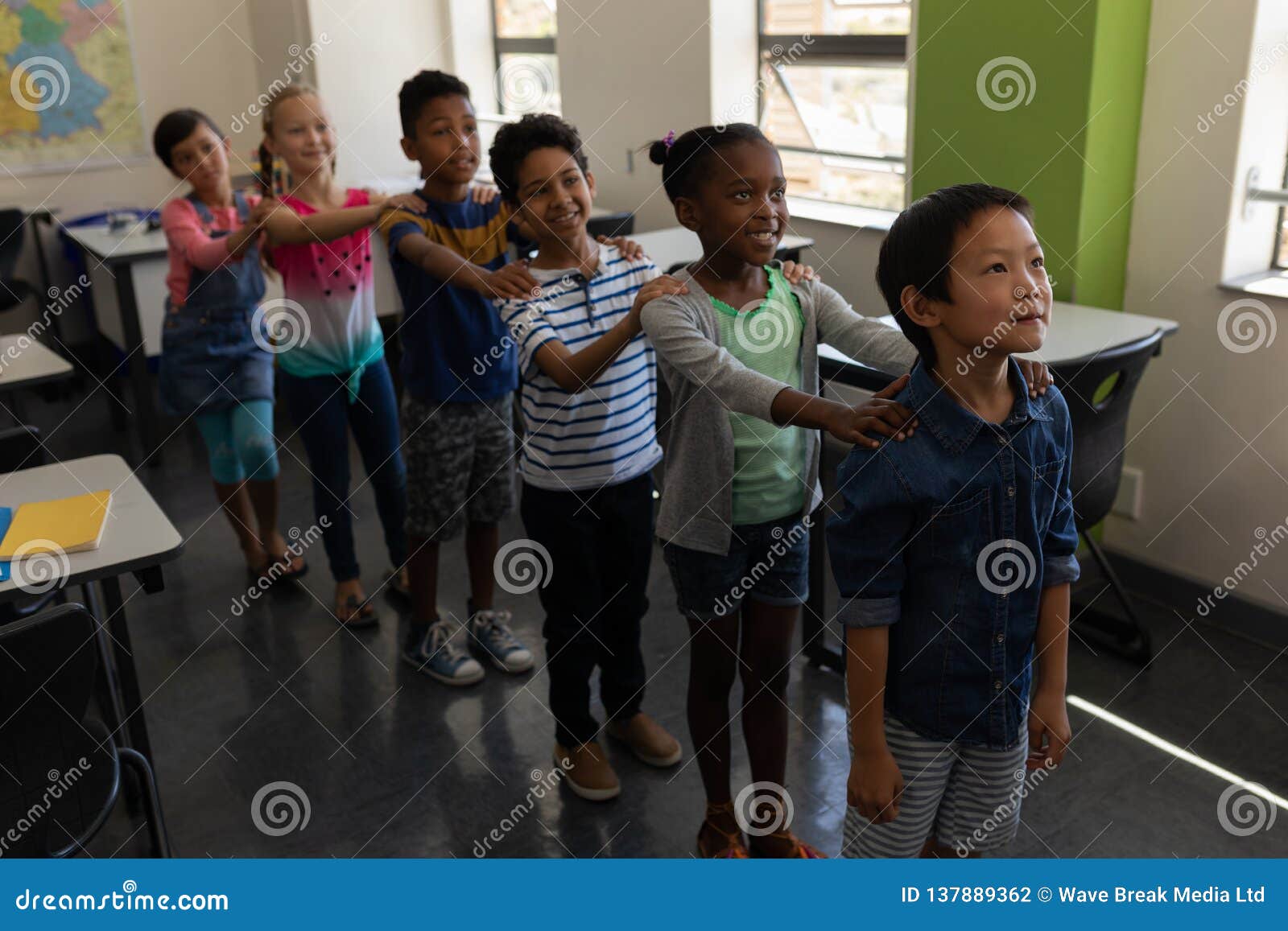 Side View of School Kids Standing in Row with Their Hands on Shoulder ...