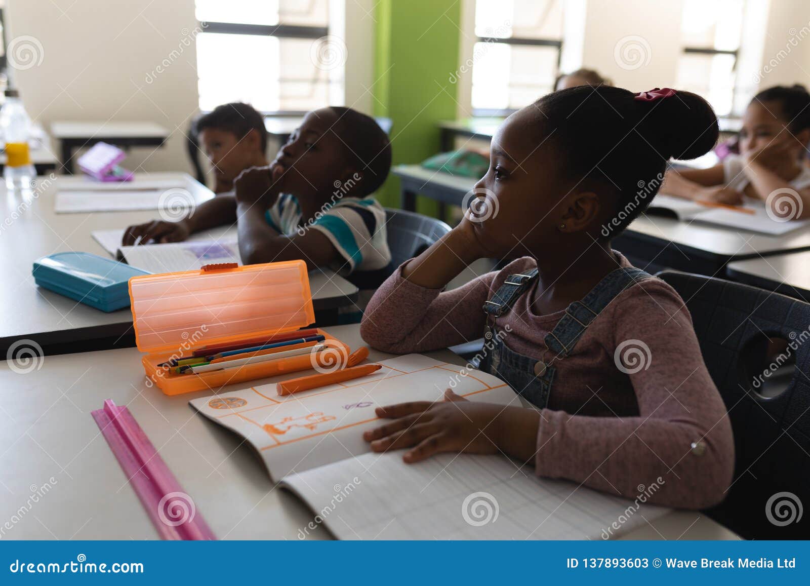 Side View of Schoolkids Studying and Sitting at Desk in Classroom Stock ...