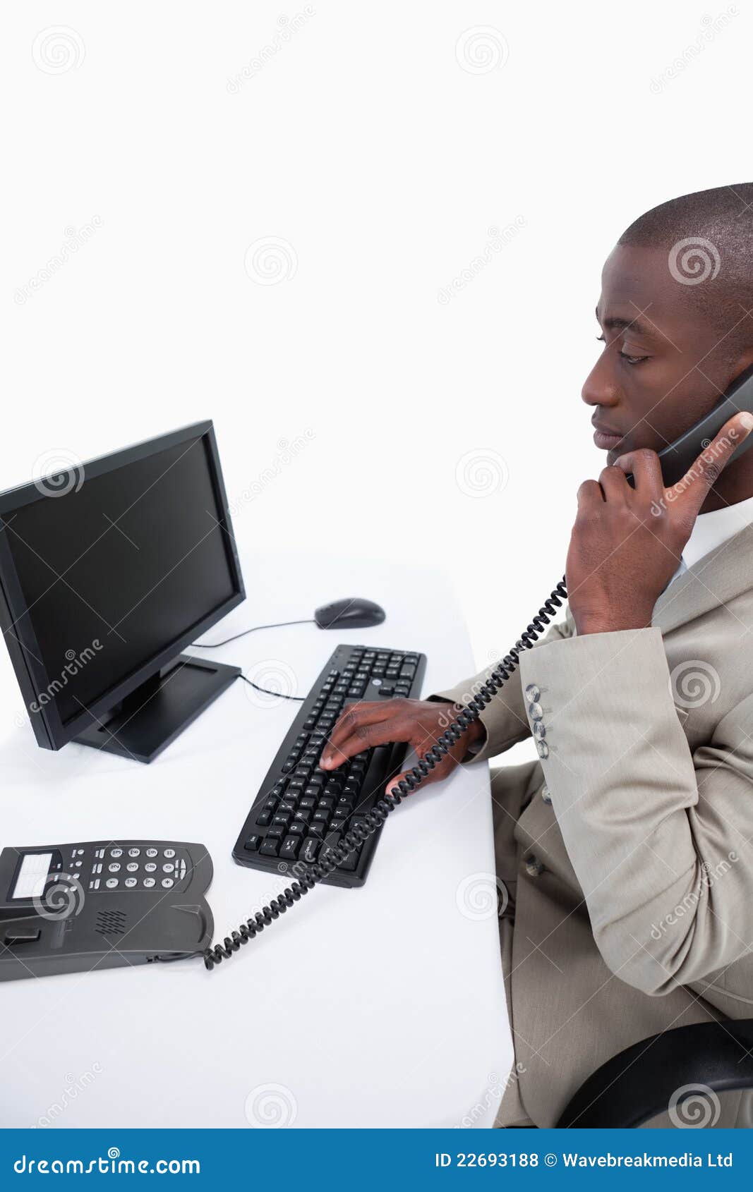 Side View of a Secretary Answering the Phone while Using a Computer ...