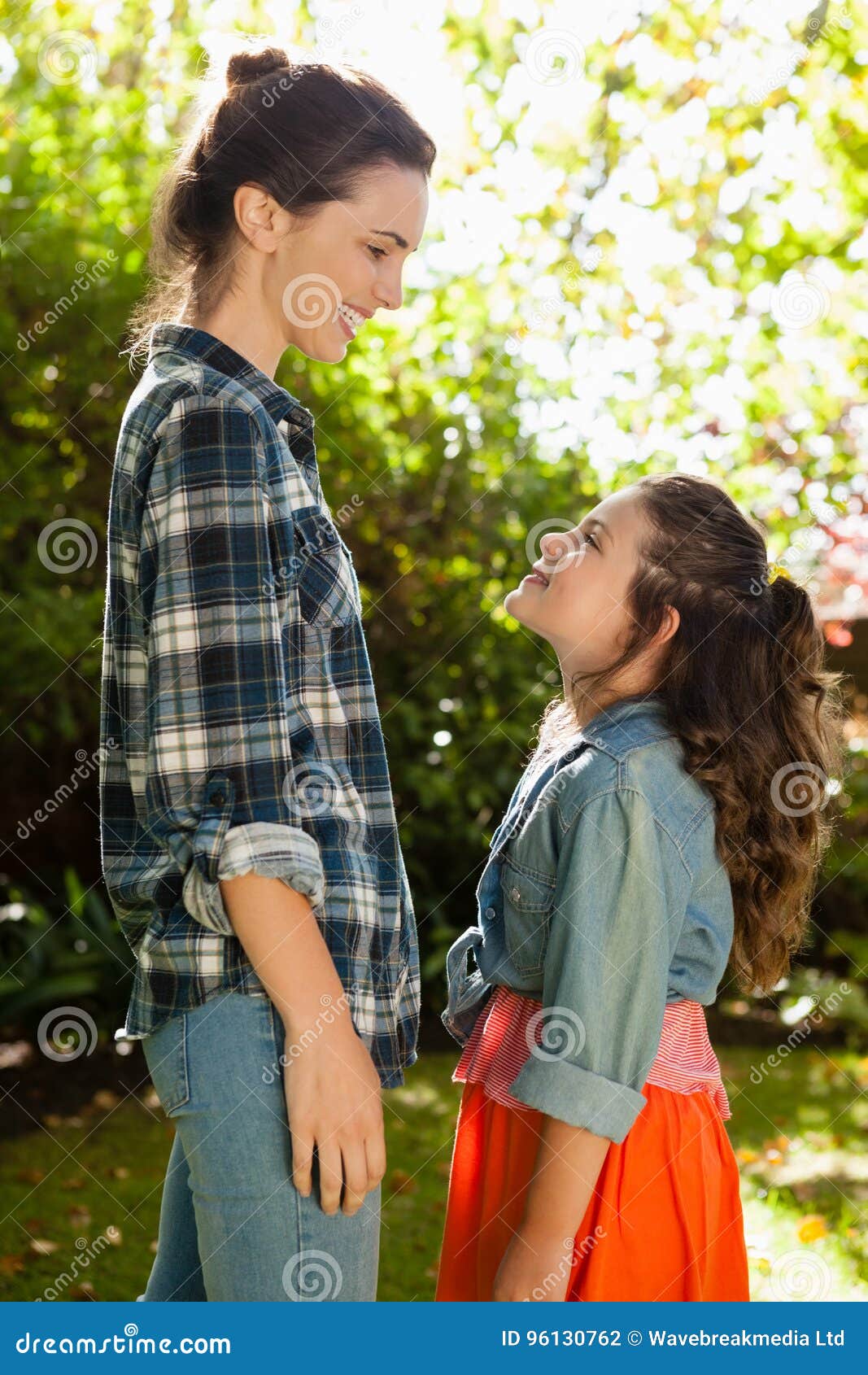Side View of Smiling Mother and Daughter Standing in Backyard Stock ...