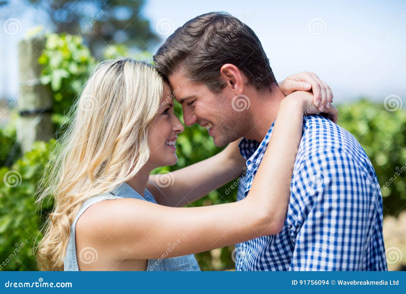 Side View of Smiling Young Couple Embracing at Vineyard Stock Photo ...