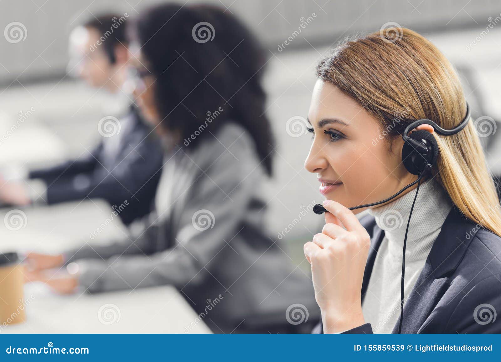 Side View of Smiling Young Woman in Headset Working with Colleagues ...