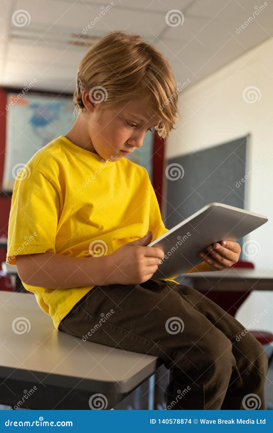 Boy Sitting Over Desk and Using Digital Tablet in a Classroom Stock ...