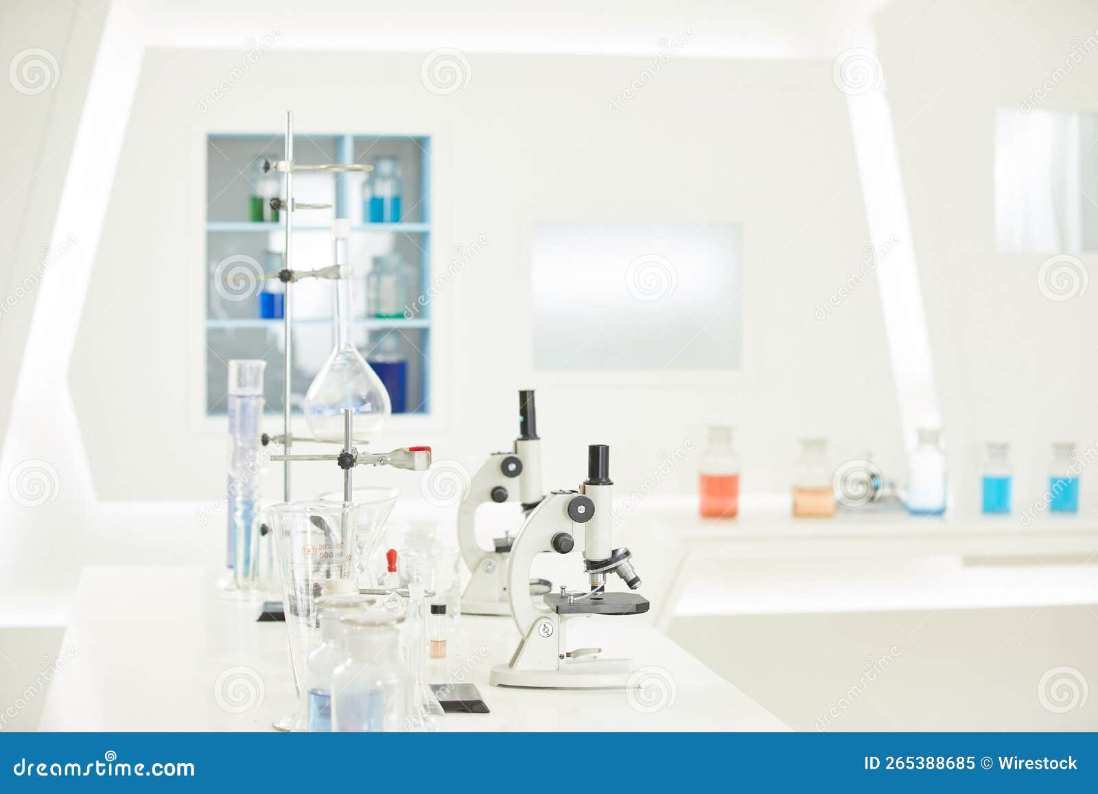 Side View of Two Microscopes Next To Beakers Filled with Fluid and ...