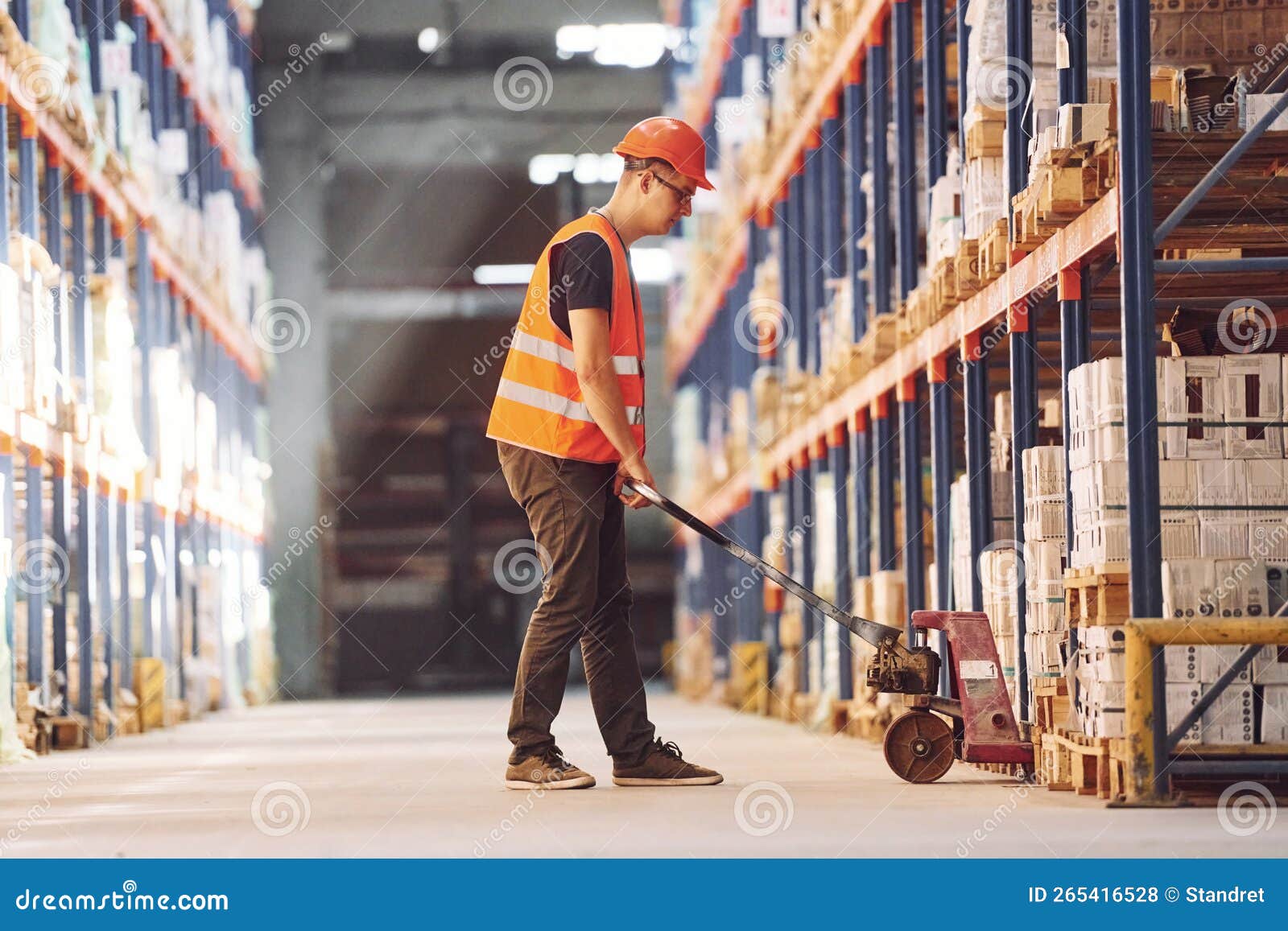 Side View of Warehouse Worker that is in Uniform and Hard Hat Working ...