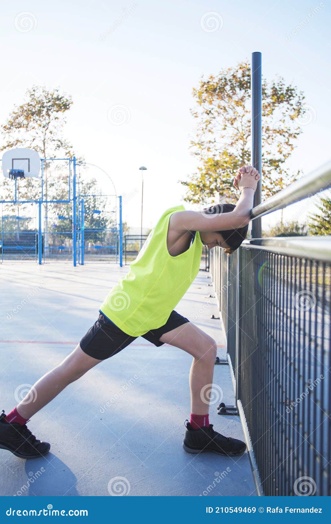 Side View of a Young Basketball Player Stretching Legs before Playing ...