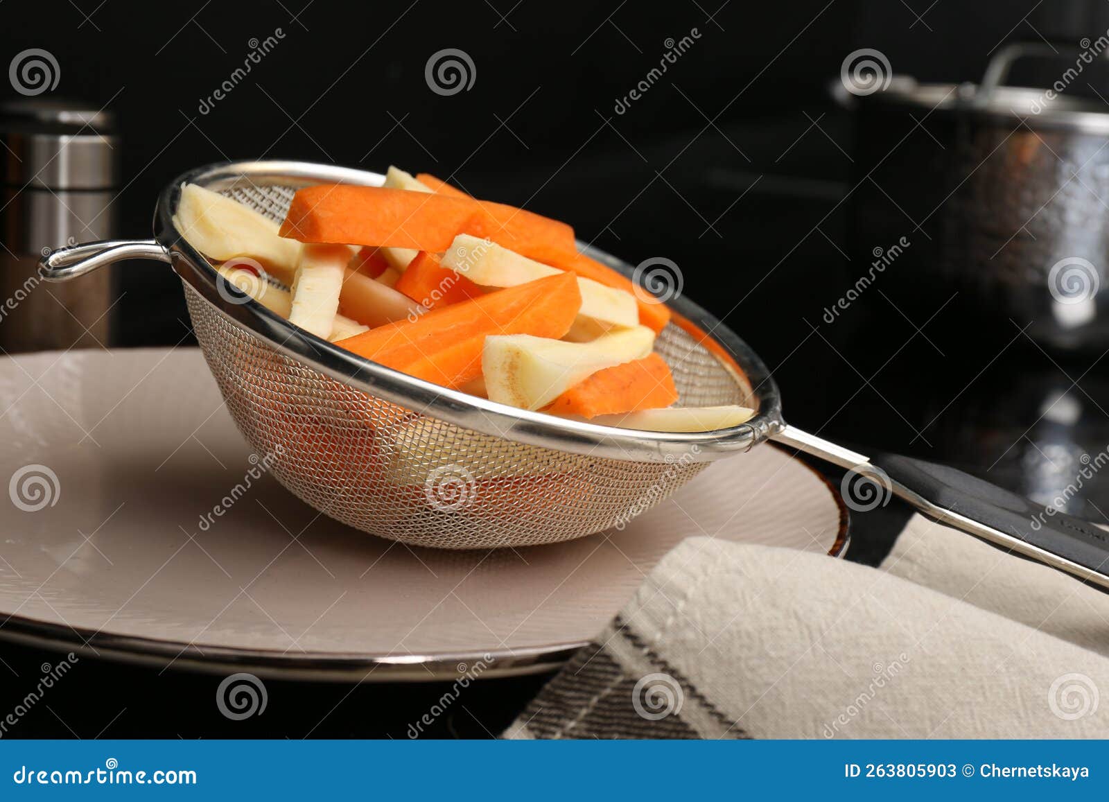 Sieve with Cut Raw Parsnips and Carrots on Black Table in Kitchen Stock ...