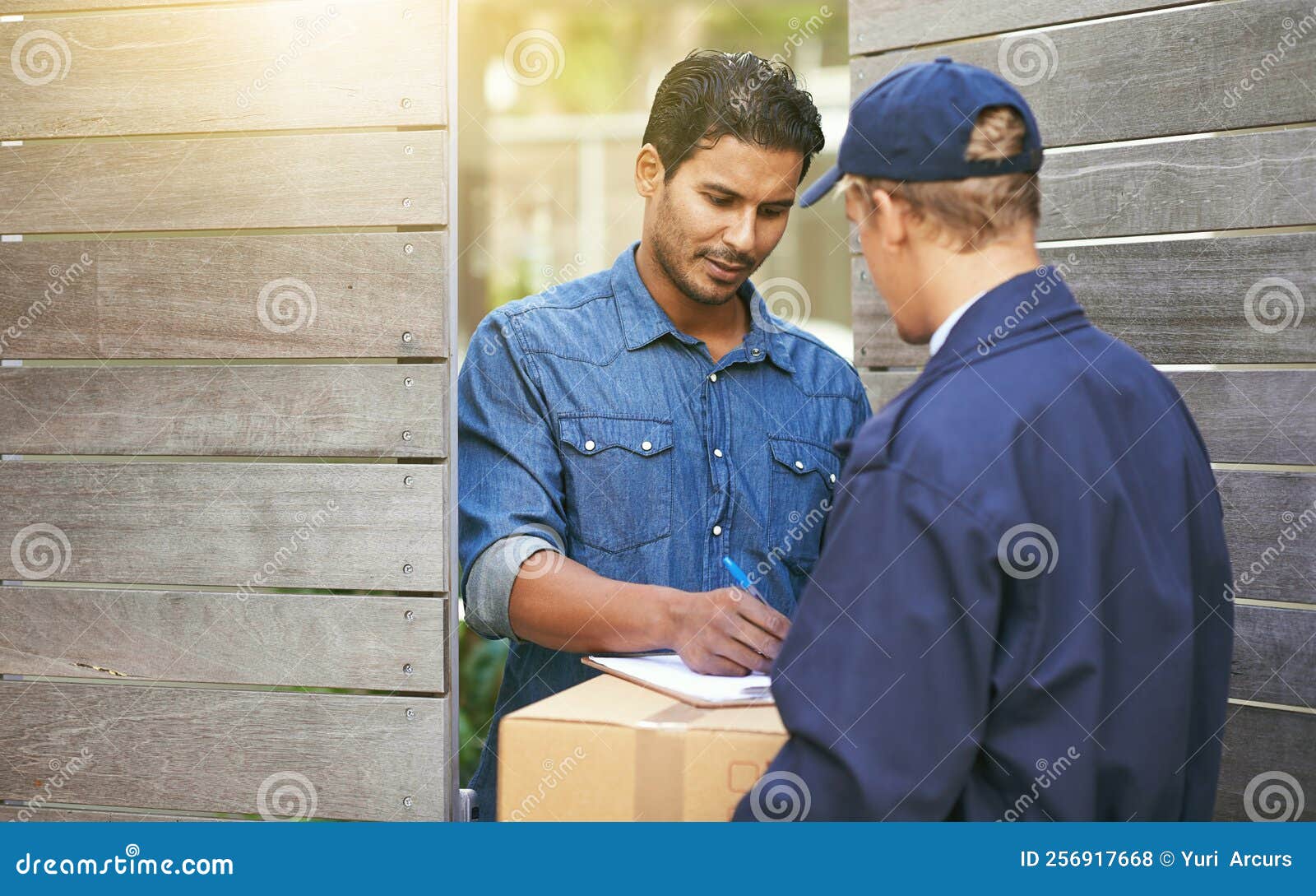 Signing for His Package. a Young Man Receiving a Package at Home. Stock ...
