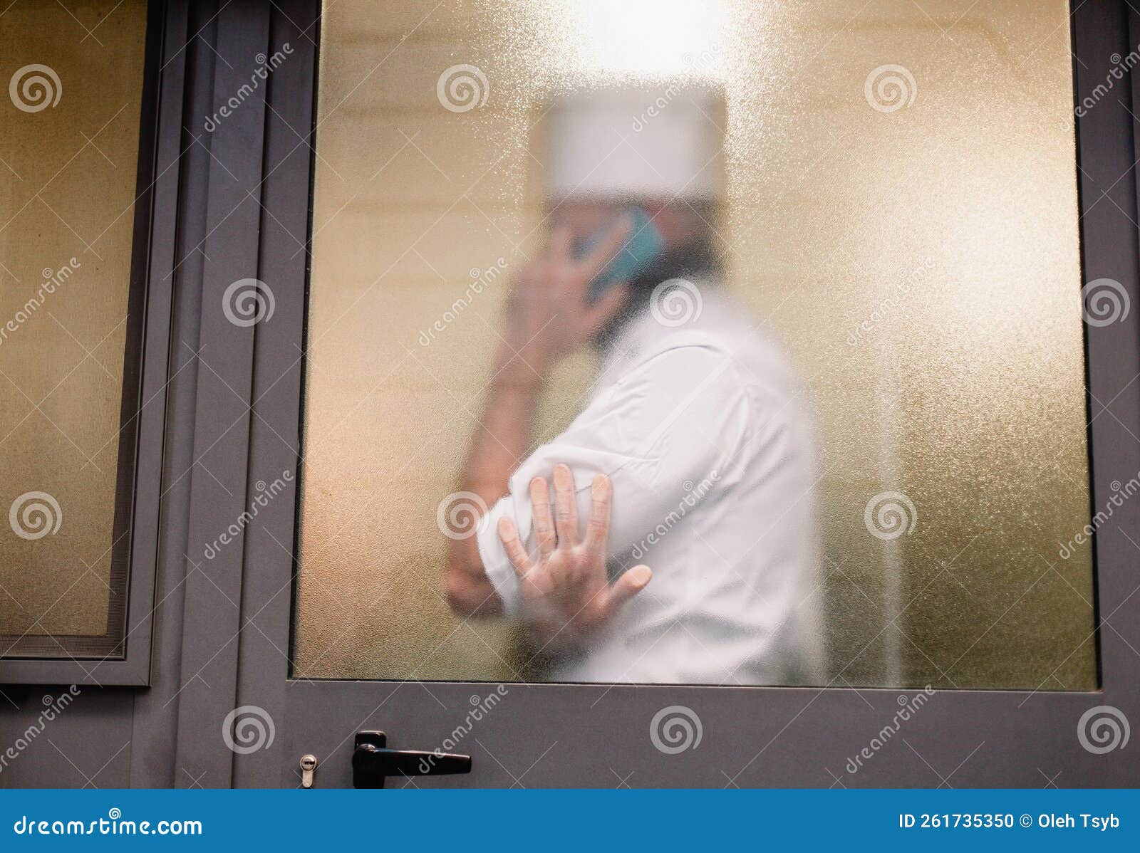 Silhouette Behind the Glass of a Man in a Chef`s Uniform Talking on the ...